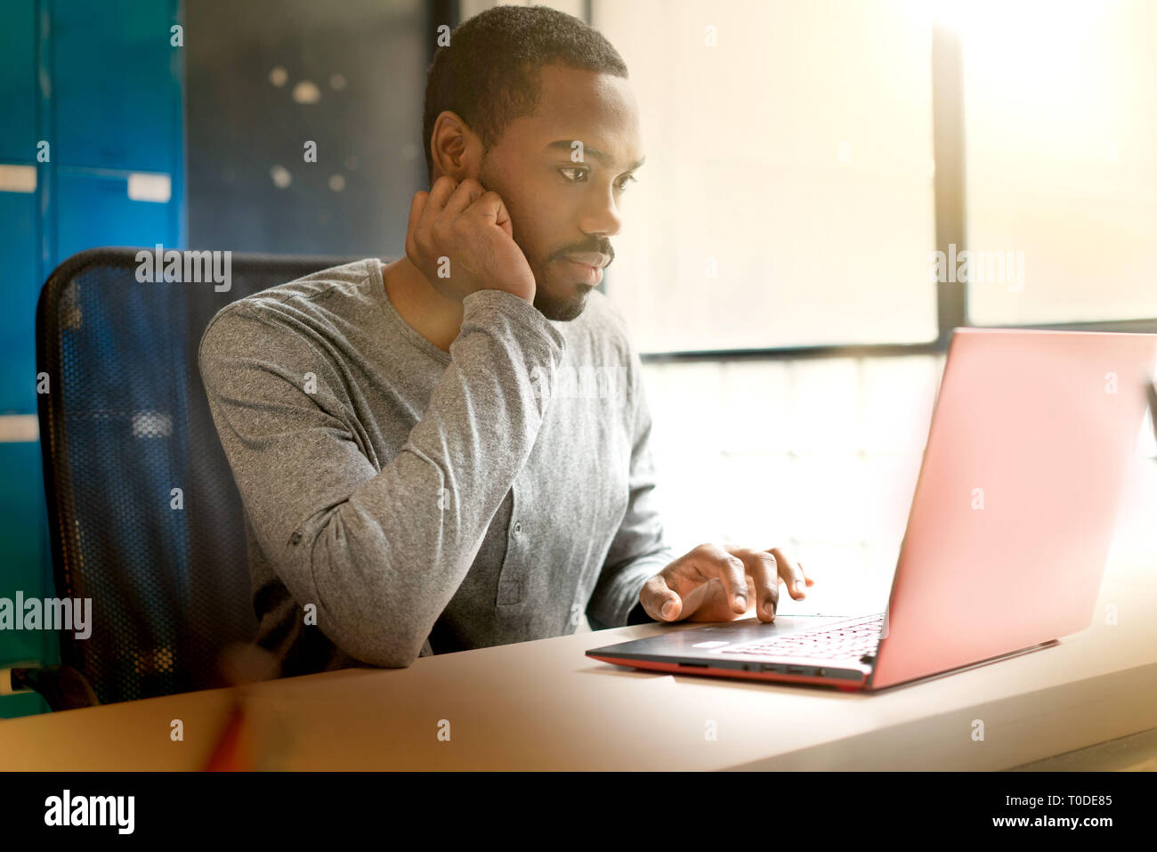 Attractive young black man working in modern office space Stock Photo ...