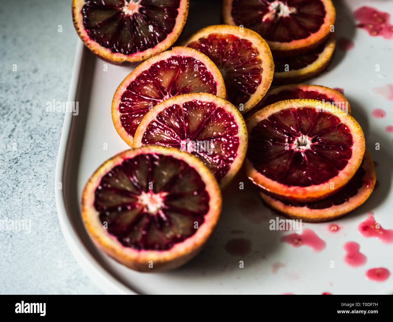 Raw blood red orange slice on oval plate a gray background. Citrus ...