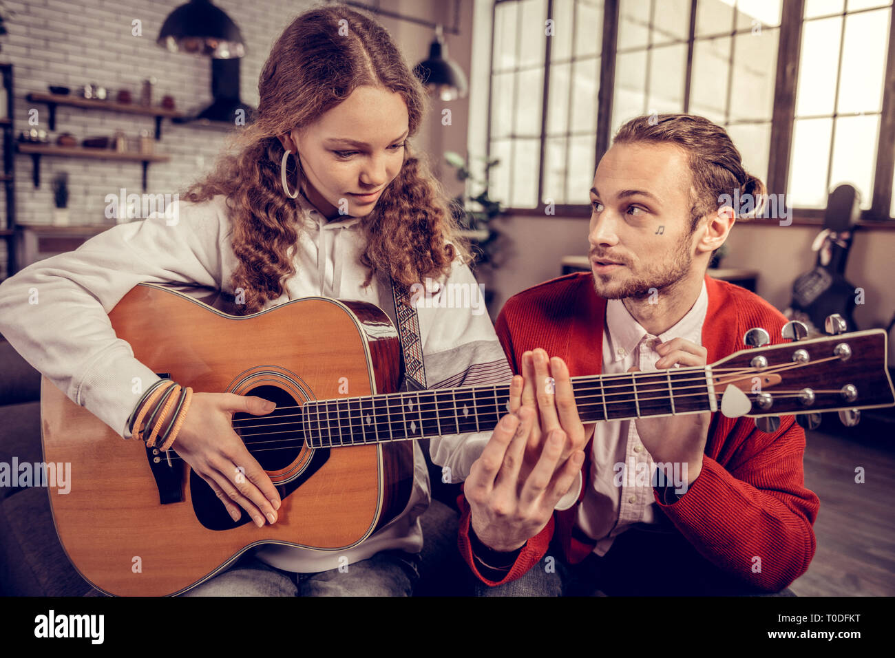Older brother helping his cute teenage sister playing the guitar Stock ...