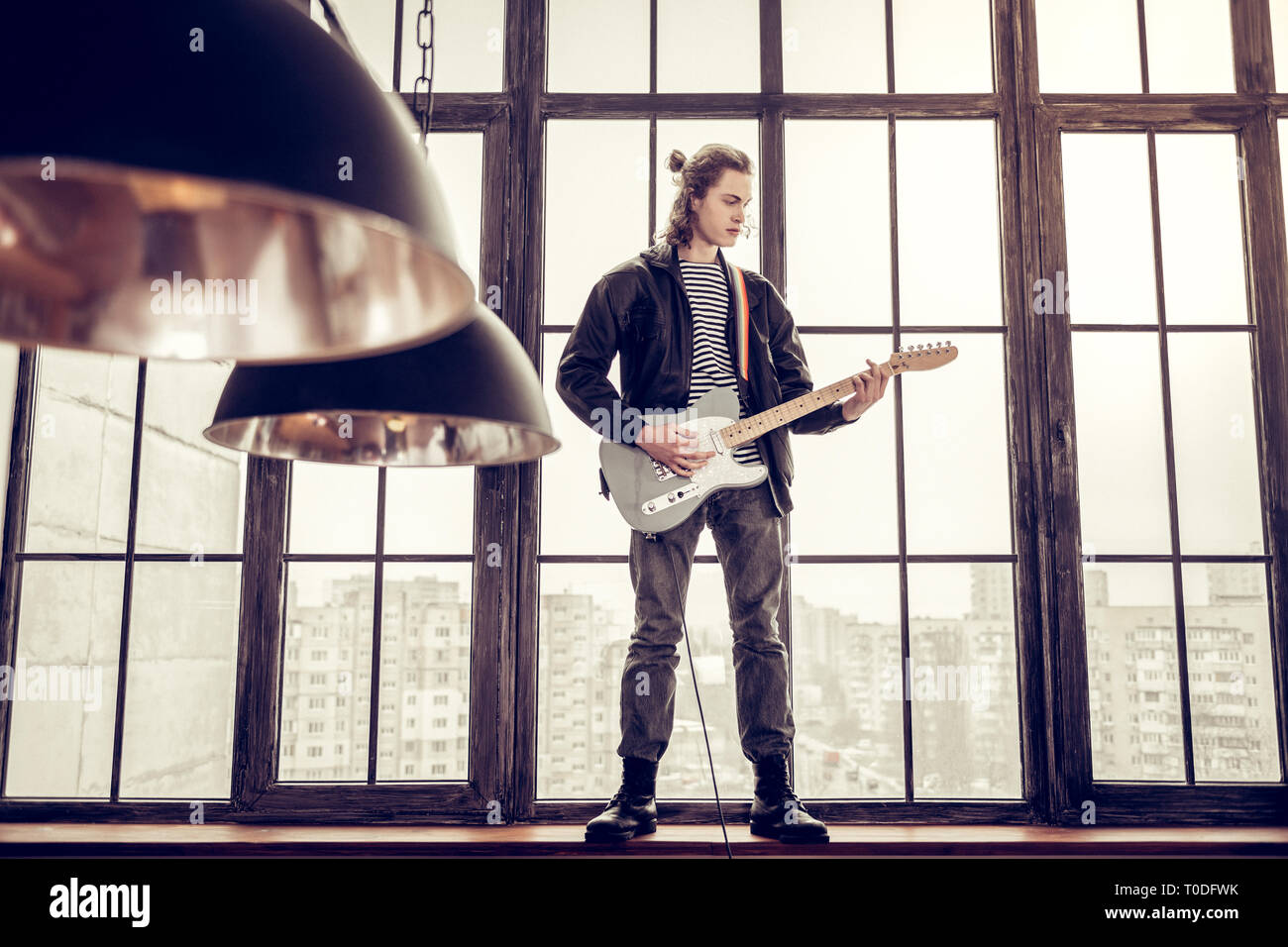 Rock musician standing on window sill and playing the guitar Stock ...