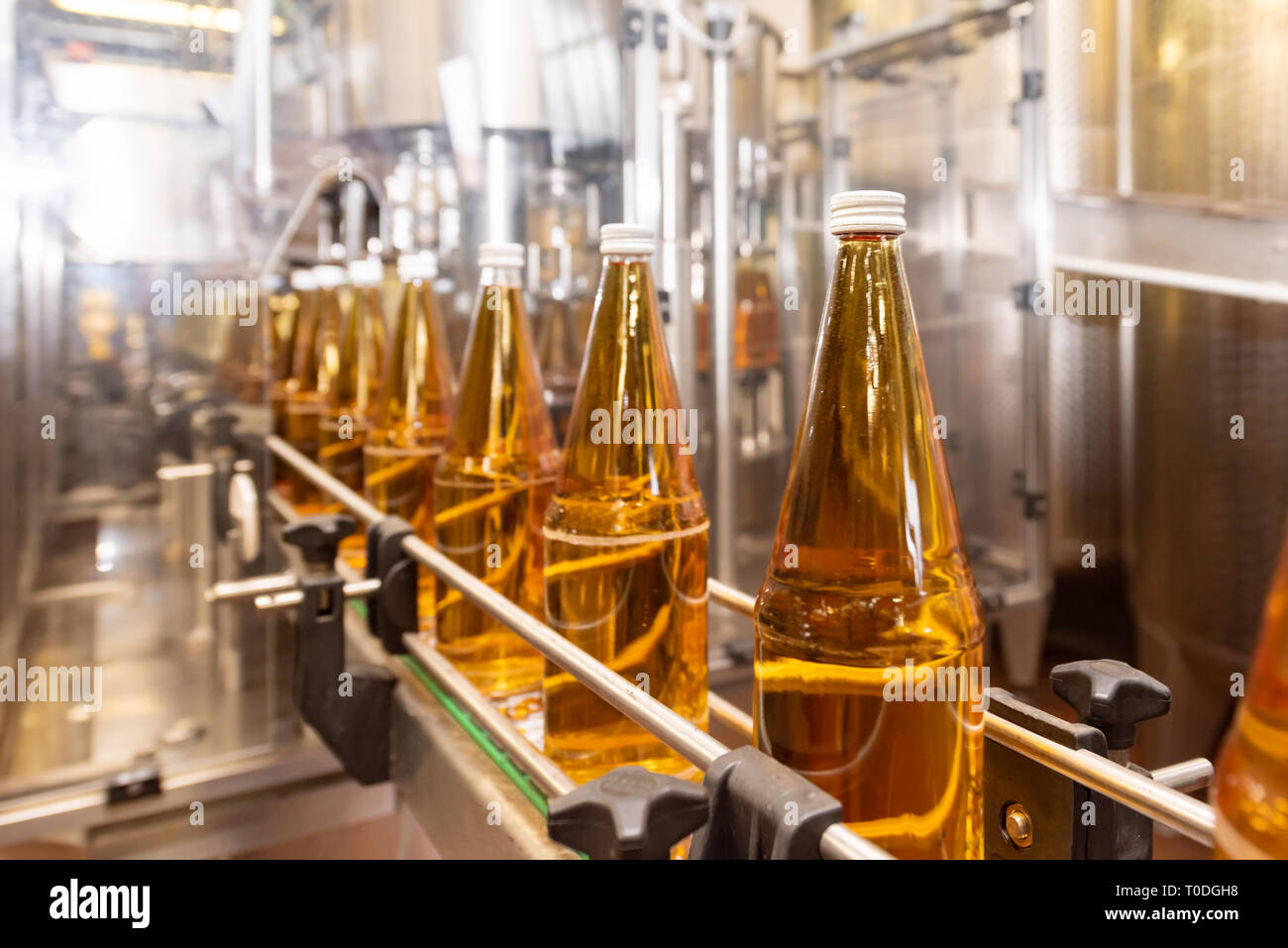 Filling glass bottles with juice. Bottling of drinks. bottling plant ...