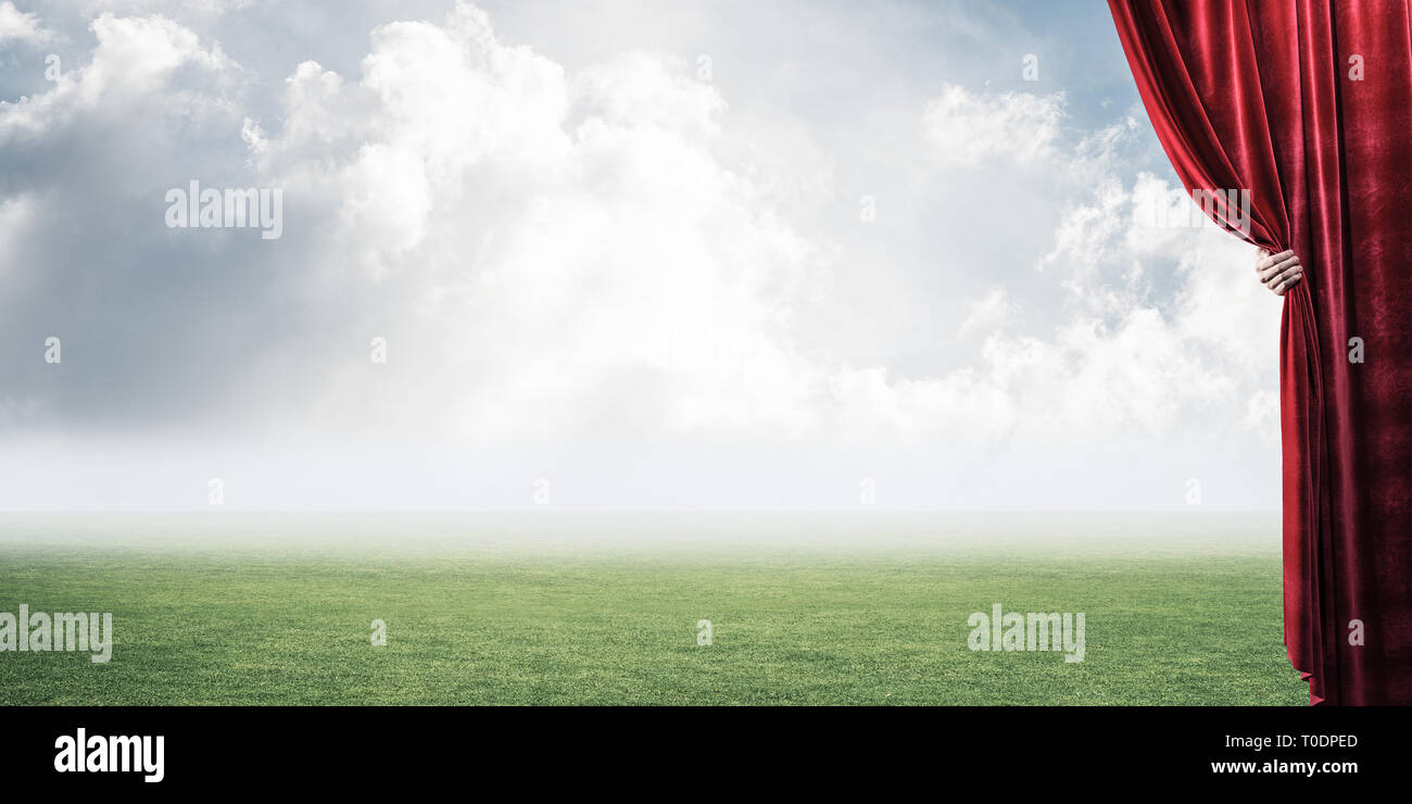 Green meadow behind red curtain and hand holding it Stock Photo - Alamy