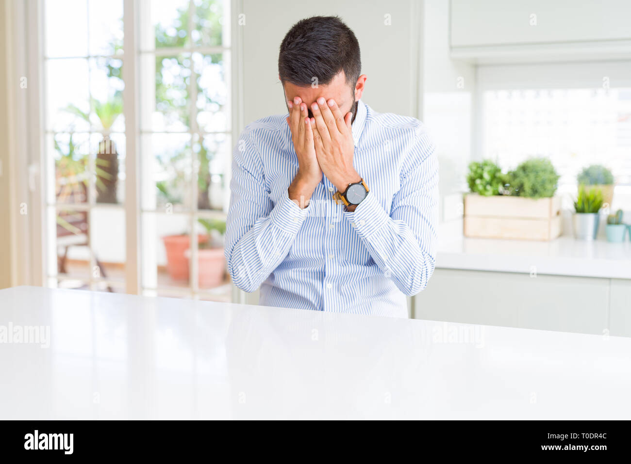Handsome hispanic business man with sad expression covering face with ...