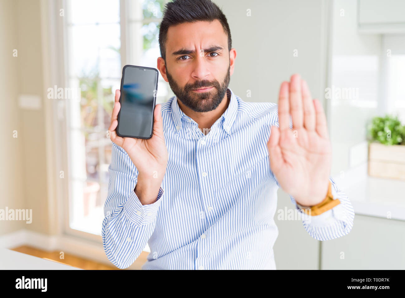 Handsome hispanic business man showing smartphone screen with open hand ... Handsome hispanic business man showing smartphone screen with open hand ...