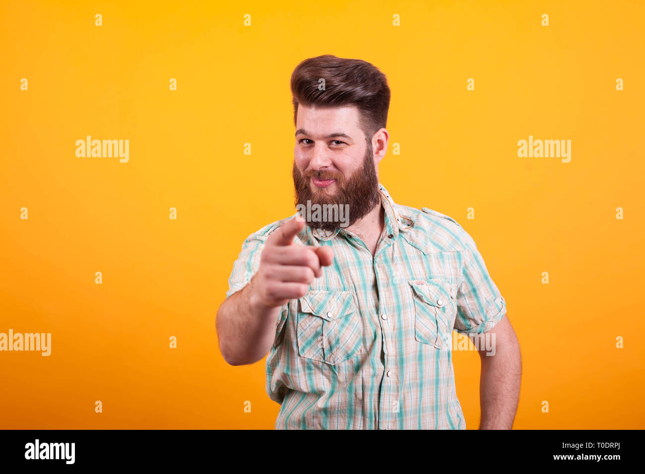 Portrait of bearded man pointing at the camera over yellow background ...