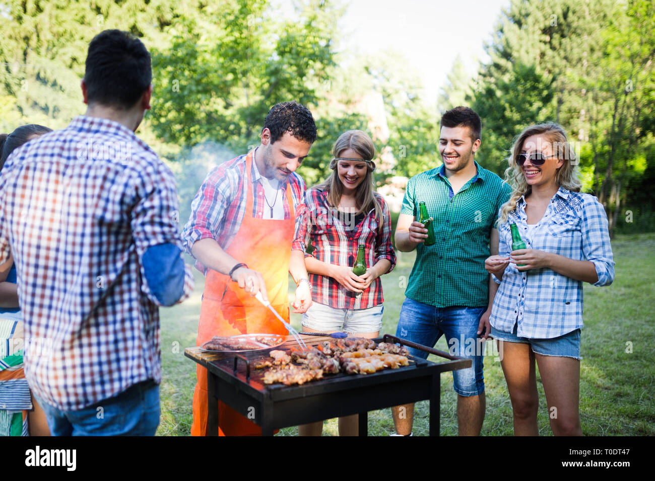 Happy students having barbecue on summer day Stock Photo - Alamy