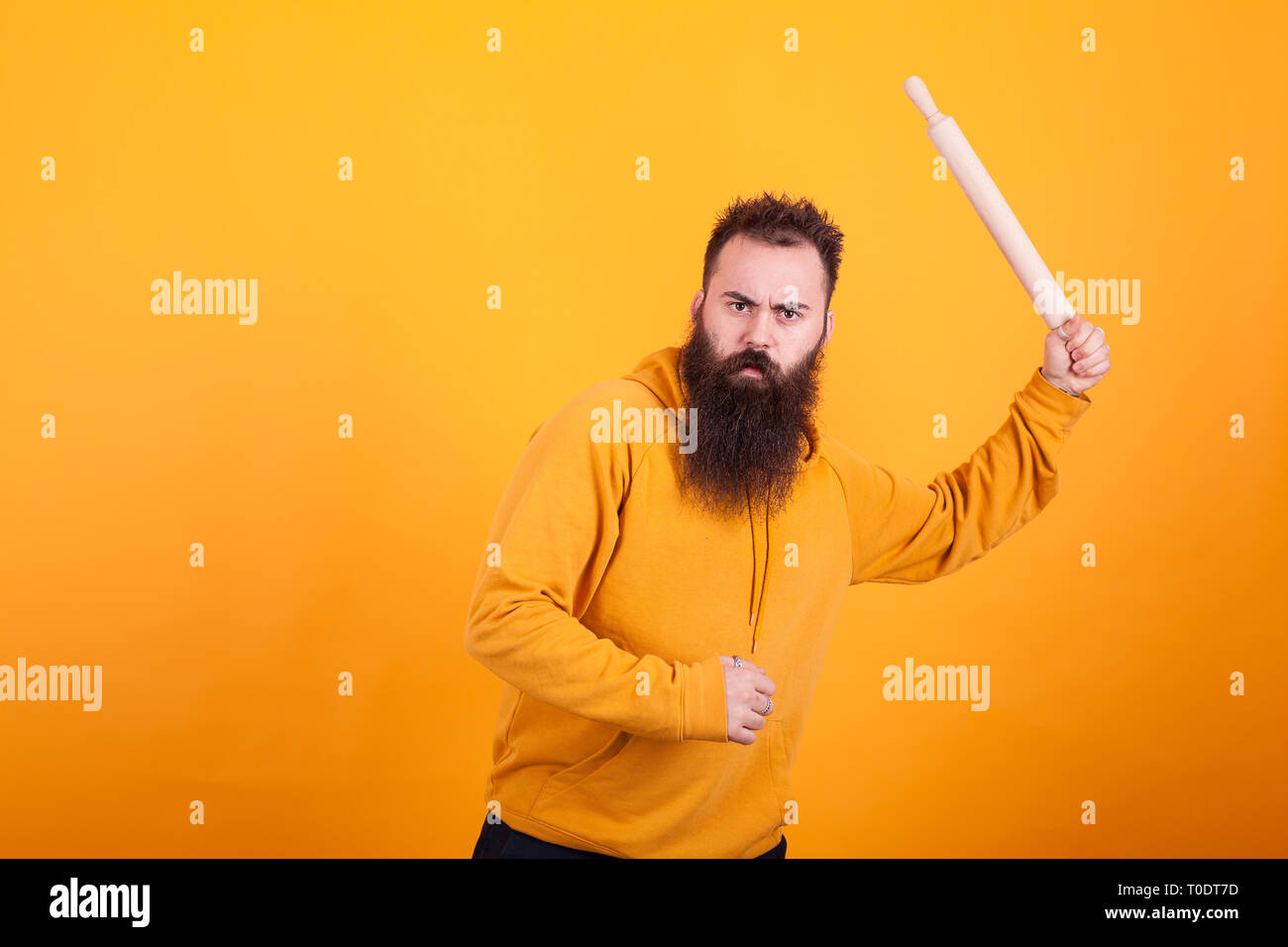 Bearded man using paddle as if was a baseball bat over yellow ...