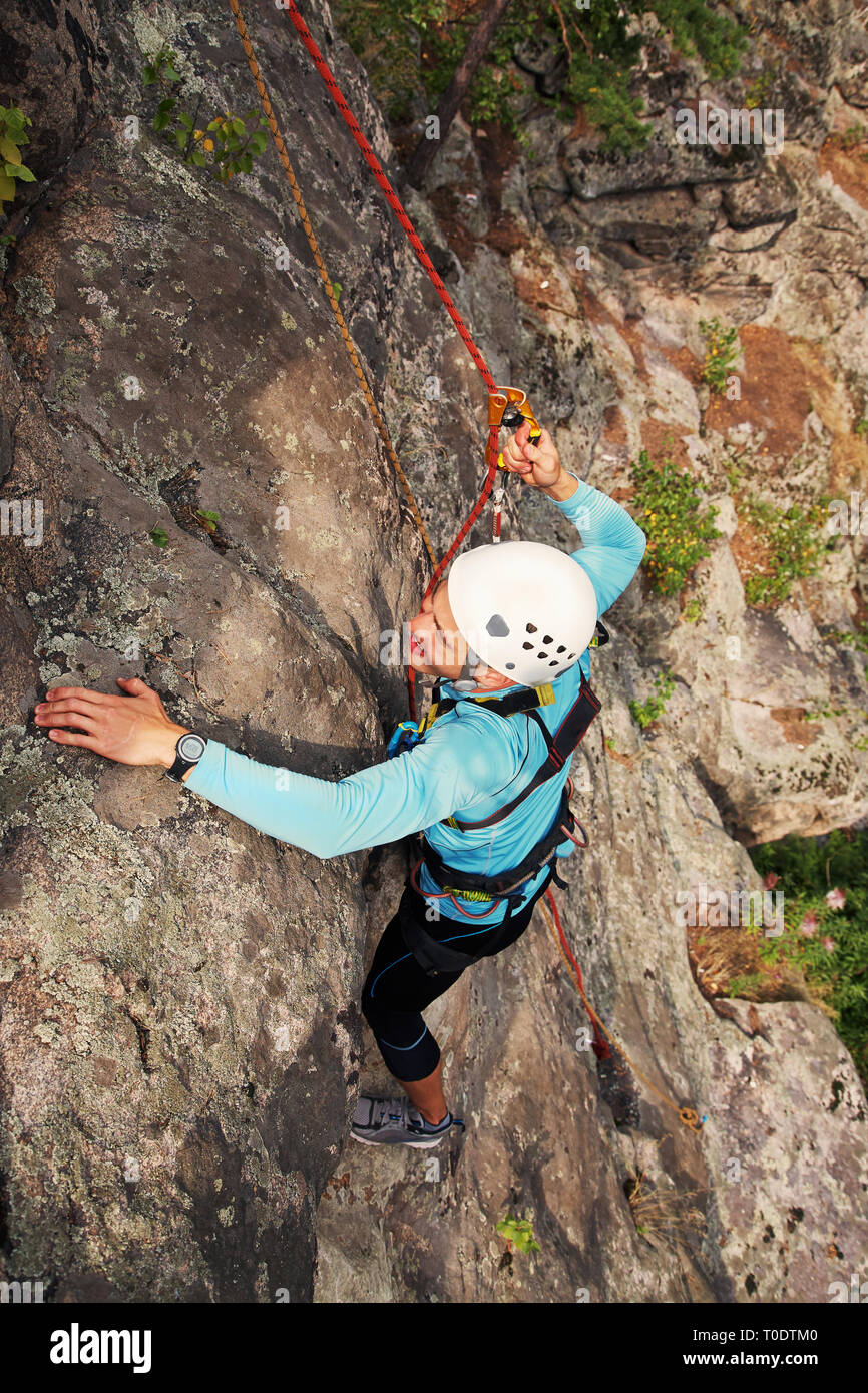 climber in helmet overcomes rocky wall with a rope insurance Stock ...