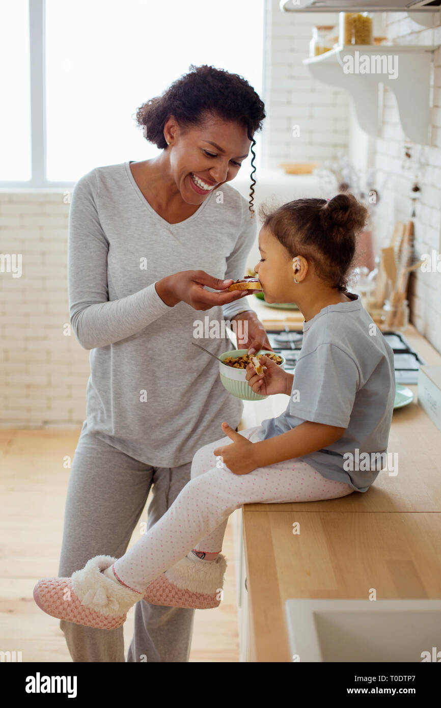 Positive delighted international female person feeding her kid Stock ...
