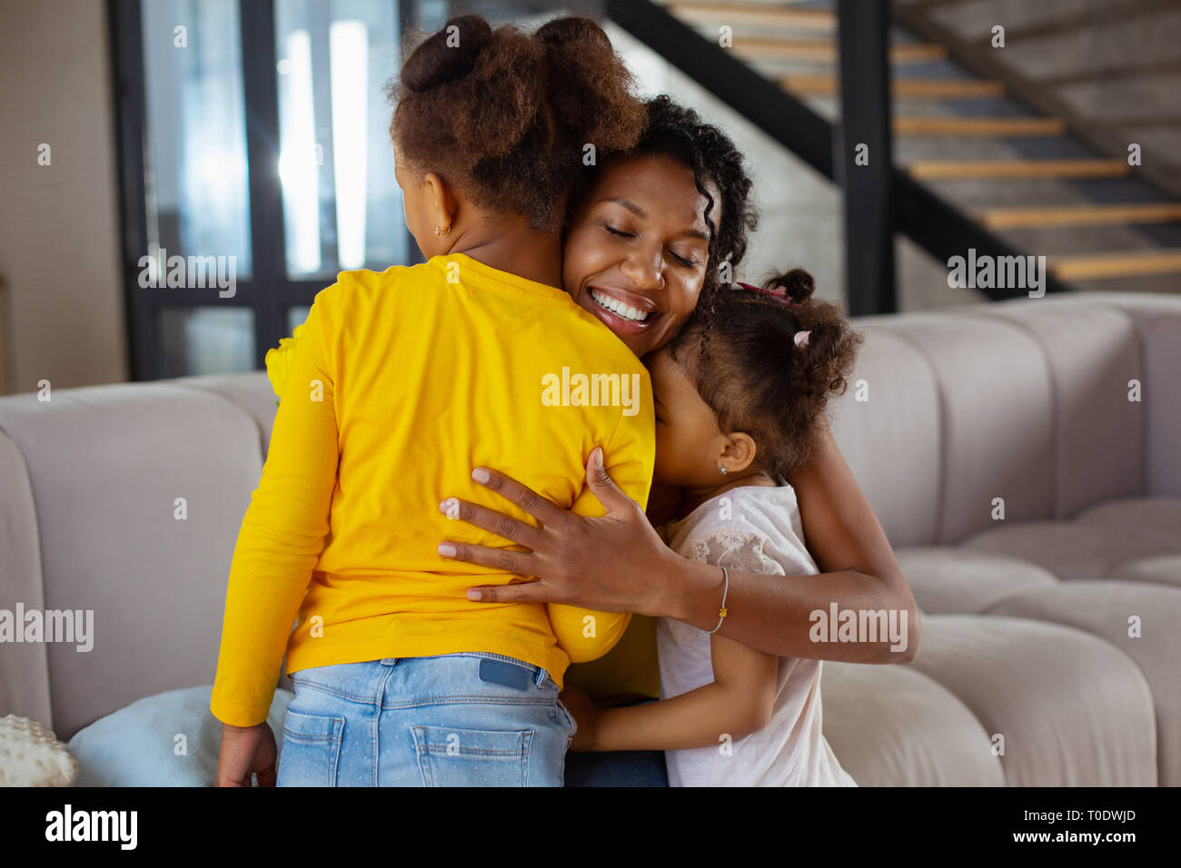 Positive delighted young woman embracing her kids Stock Photo - Alamy