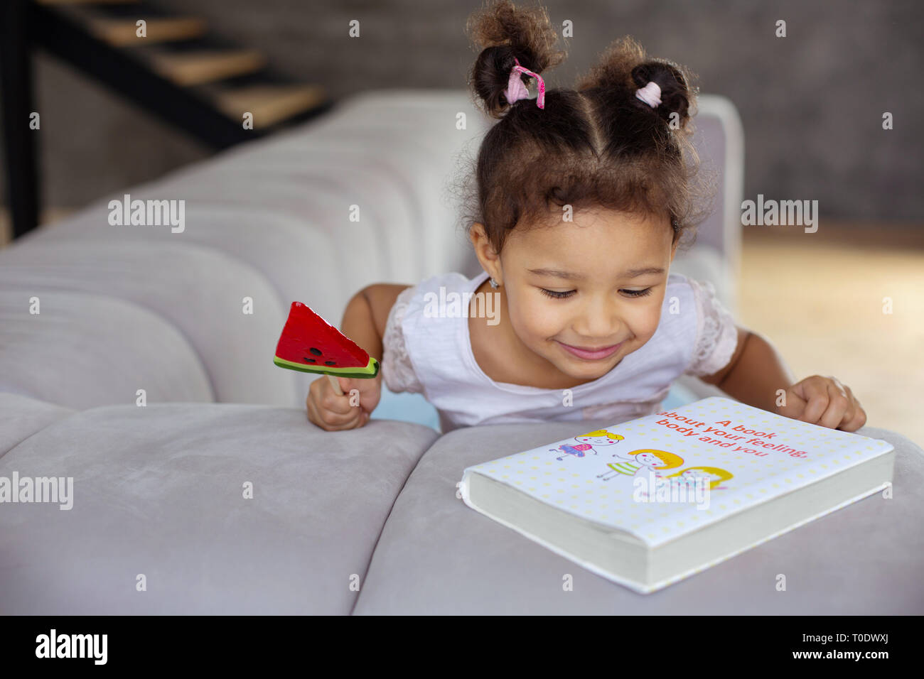 Cheerful dark-skinned girl looking at new book Stock Photo - Alamy