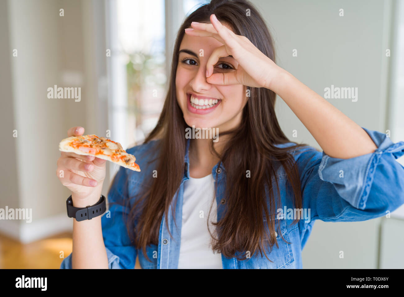 Beautiful young woman eating a slice of tasty pizza with happy face ...
