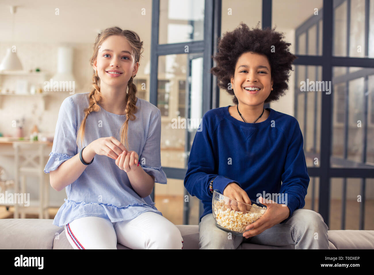Positive delighted kids eating popcorn during watching film Stock Photo ...