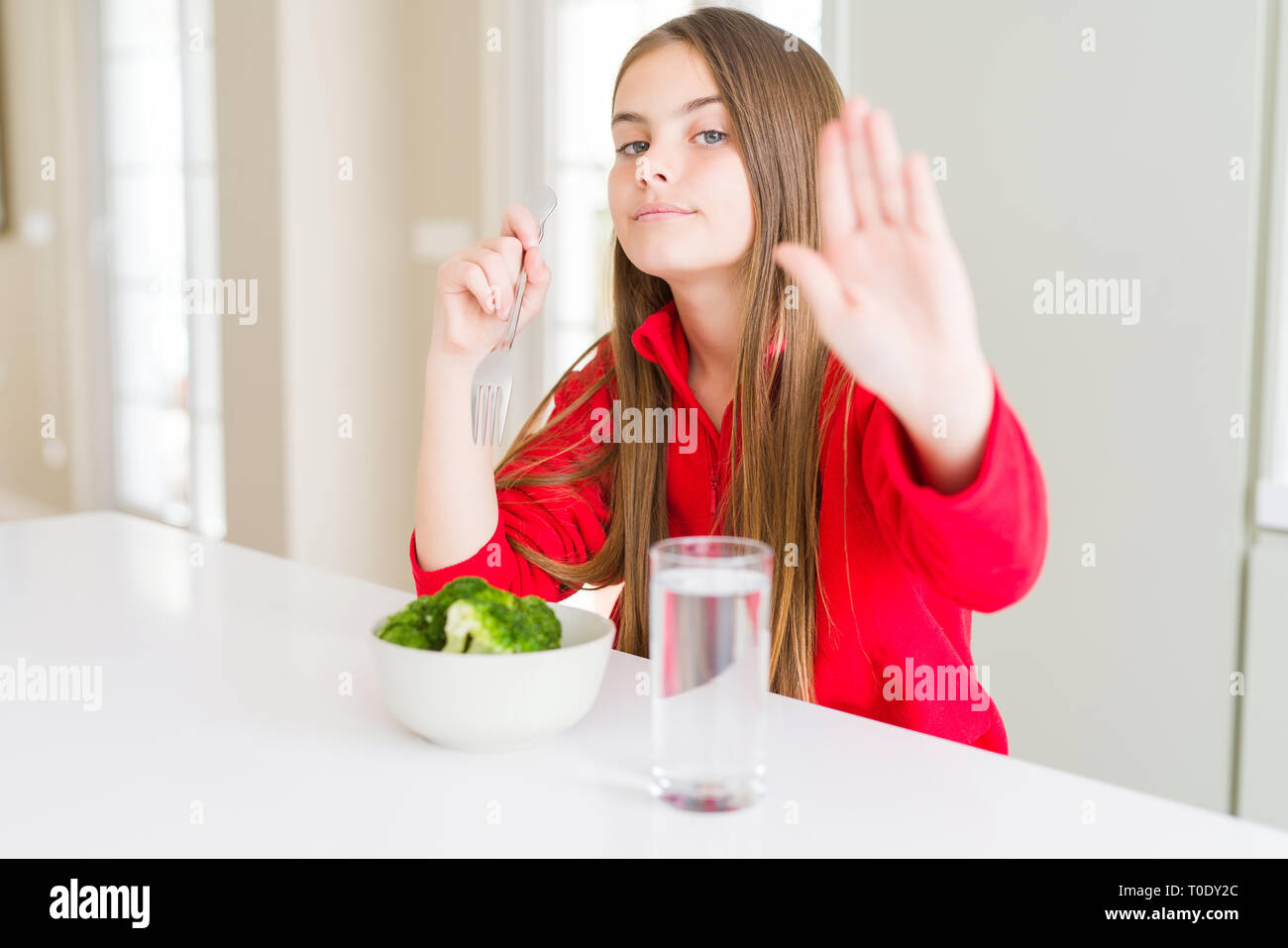 Beautiful young girl kid eating fresh broccoli and drinking water with ...
