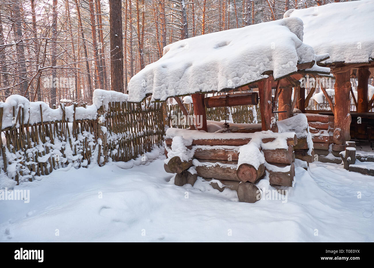 Old traditional wooden country well well made of logs covered by snow ...