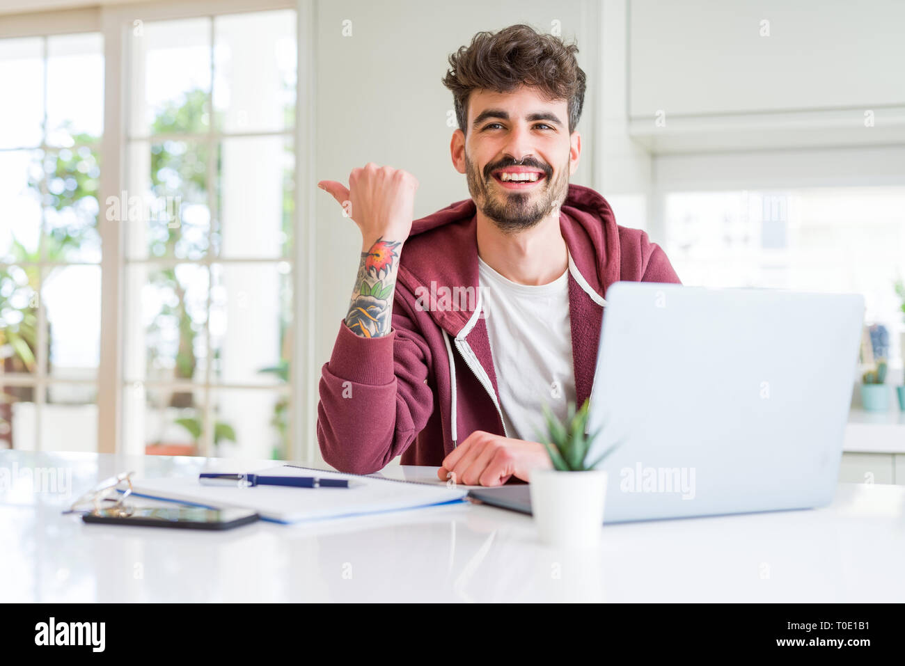 Young student man using computer laptop and notebook pointing and ...