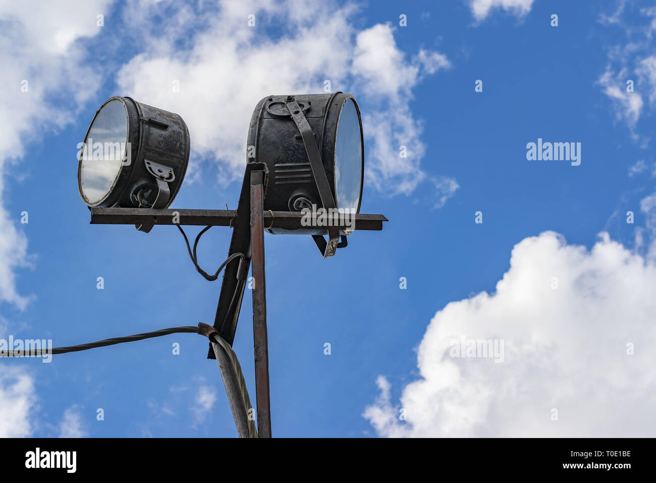 Two round black spotlights on a metal structure against a blue sky with ...
