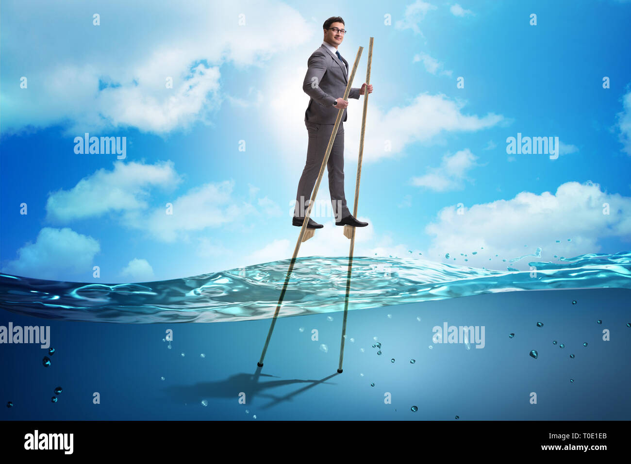 Businessman walking on stilts in water sea Stock Photo - Alamy