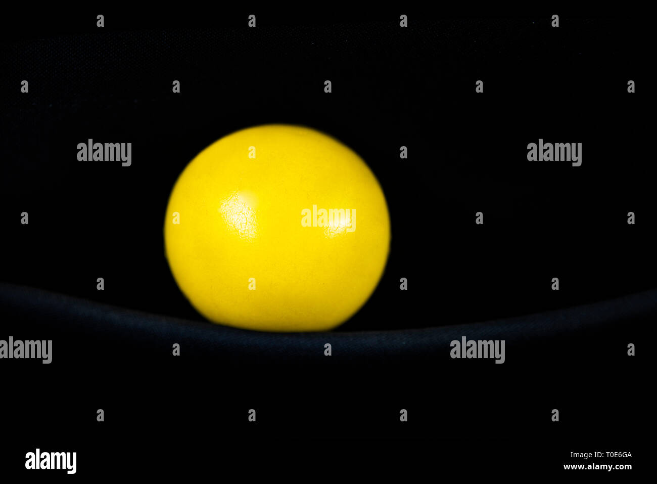 Yellow stress ball in a black background Stock Photo - Alamy