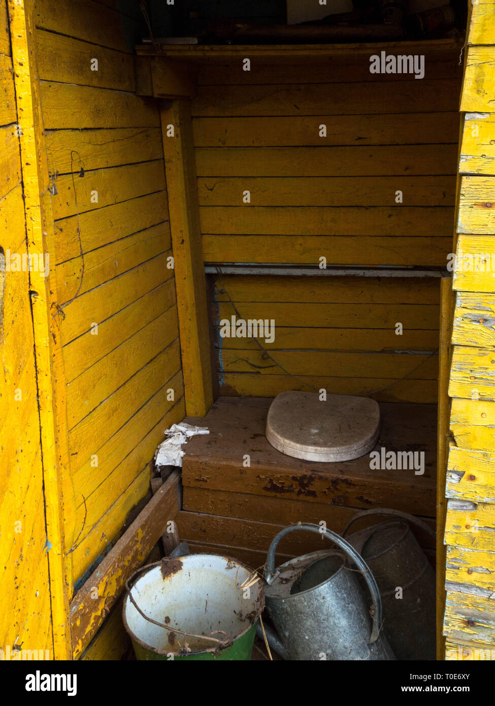 dirt wooden toilet with outdoor with dust, watering can, metal bucket ...