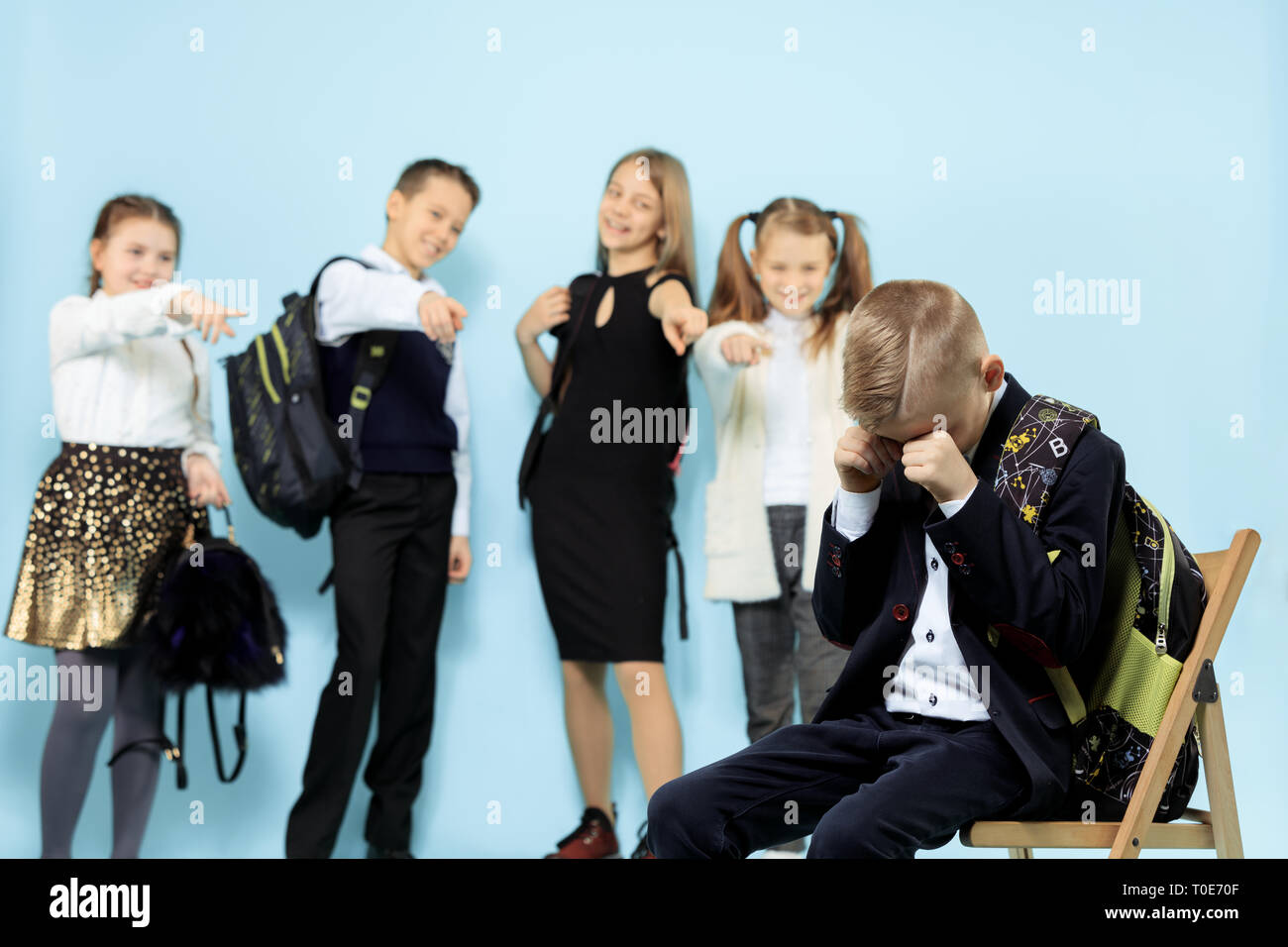 Little boy sitting alone on chair and suffering an act of bullying ...