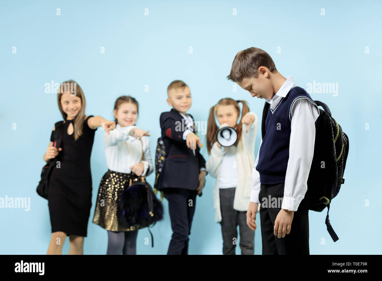 Little boy standing alone and suffering an act of bullying while ...