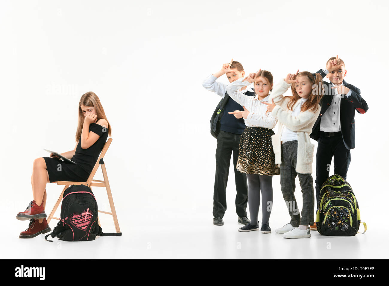Little girl sitting alone on chair and suffering an act of bullying ...