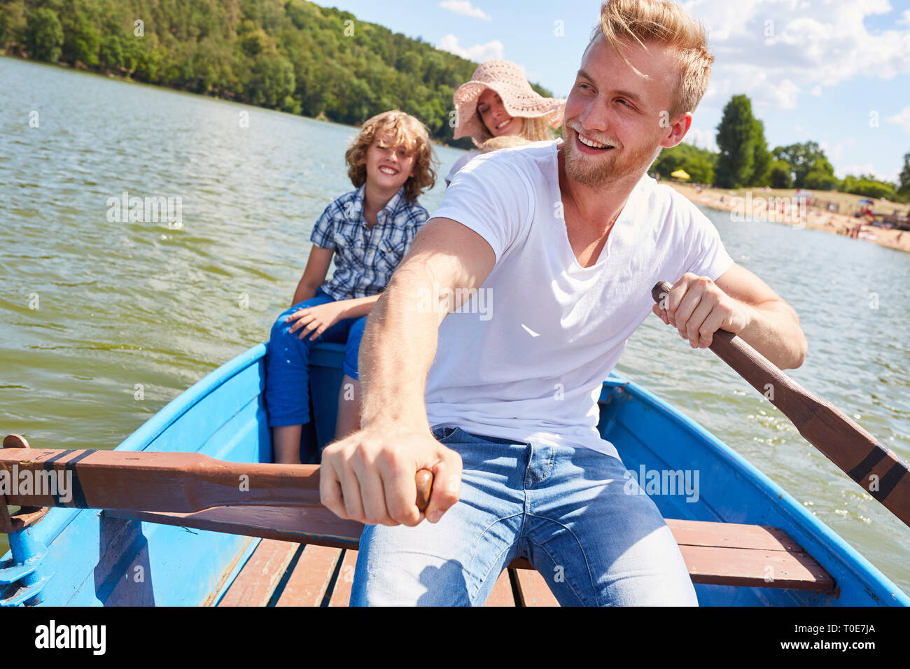 Happy father rowing his family in a boat on a lake on summer vacation ...