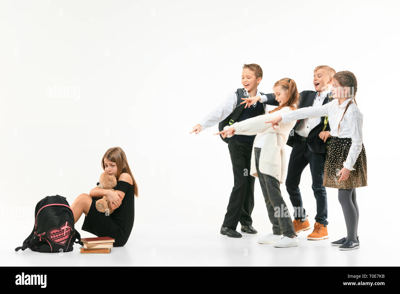 Little girl sitting alone on floor and suffering an act of bullying ...