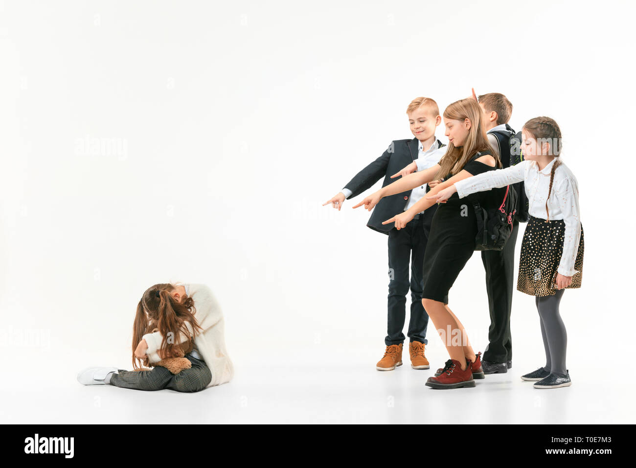 Little girl sitting alone on floor and suffering an act of bullying ...
