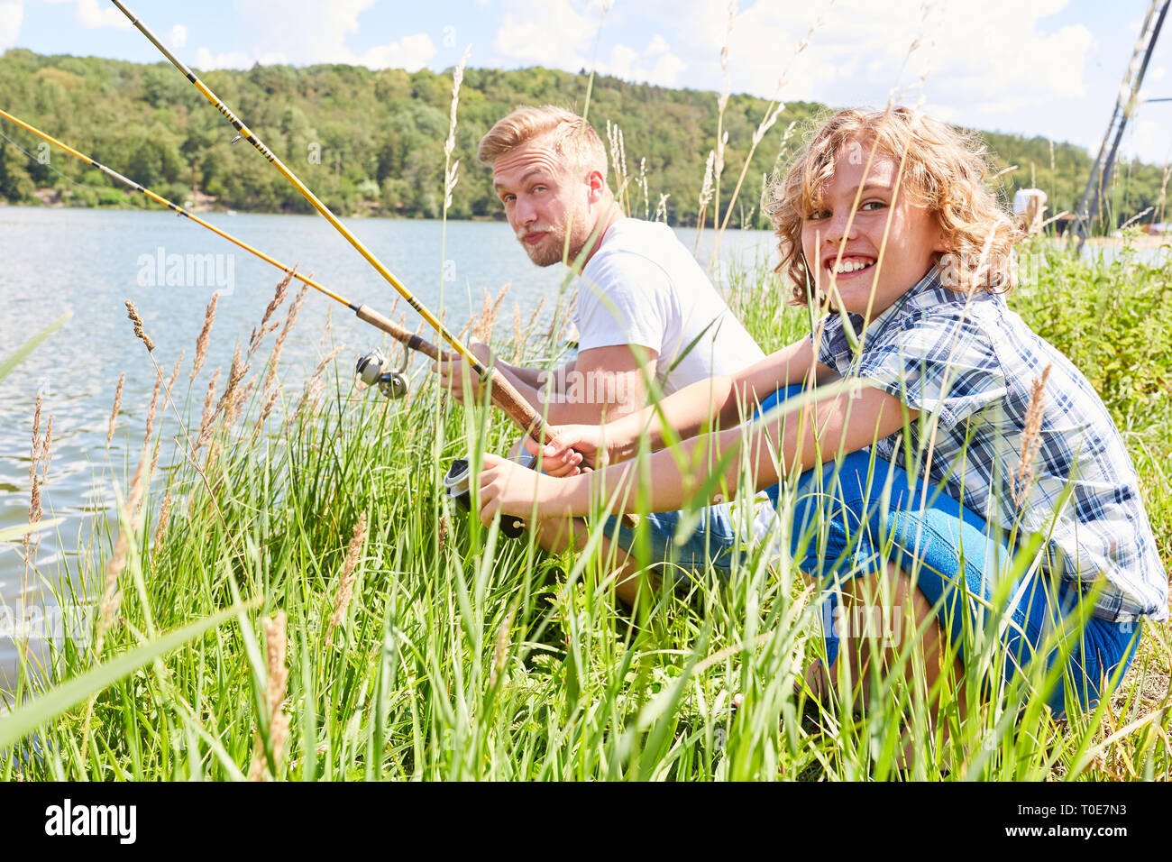 Father and son fish together at the lake during the summer holidays or ...