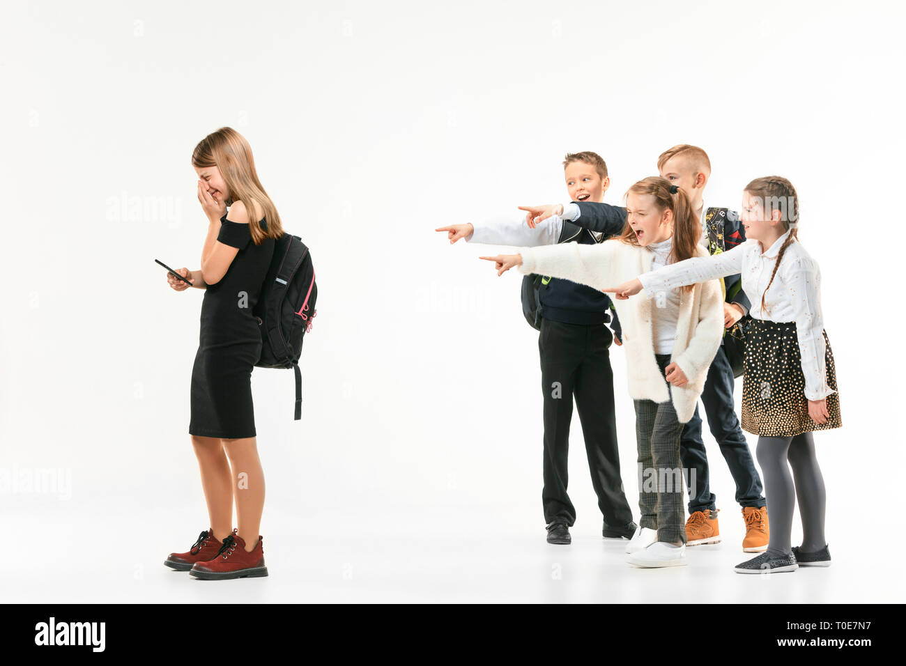Little girl standing alone and suffering an act of bullying while ...