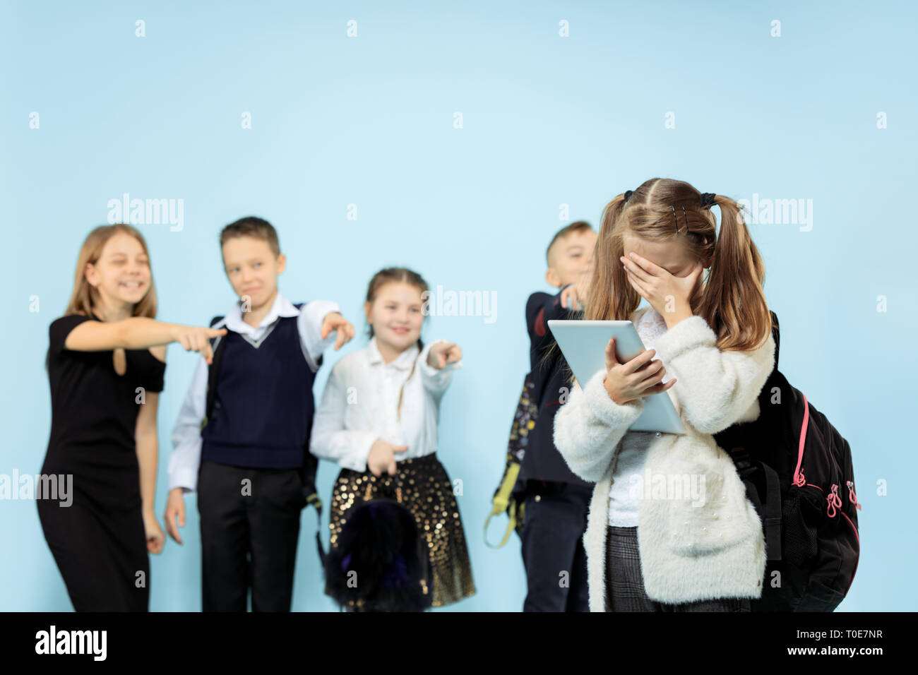 Little girl standing alone and suffering an act of bullying while ...