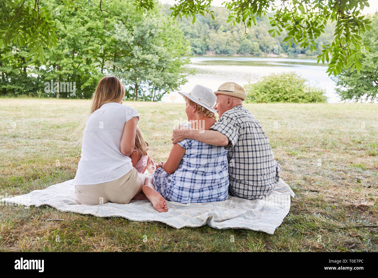 Extended family of three generations on a meadow by the lake in summer ...