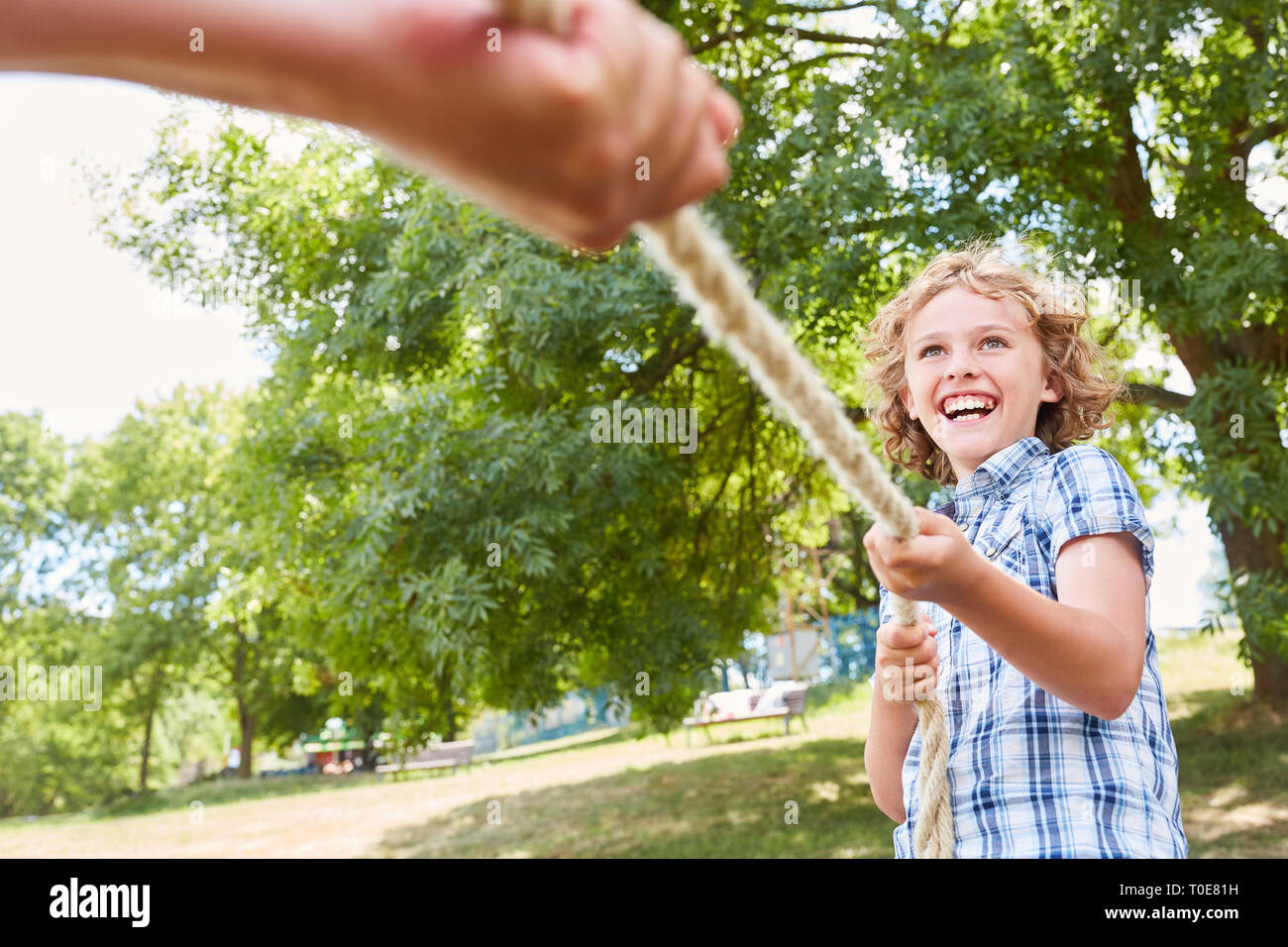 Boy in tug of war is having fun in a summer camp or summer vacation ...