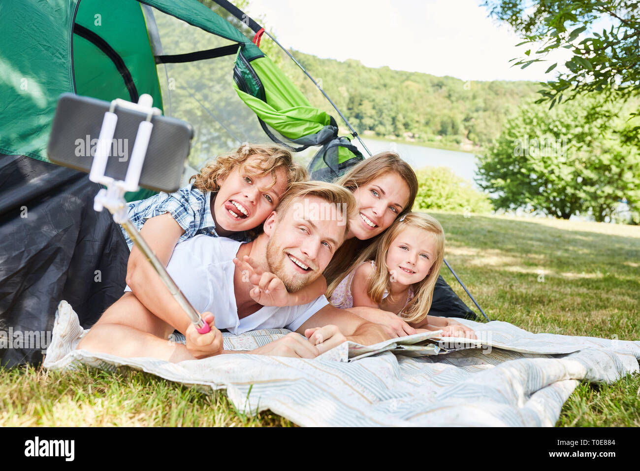 Happy family camping in the tent takes a selfie photo with smartphone ...