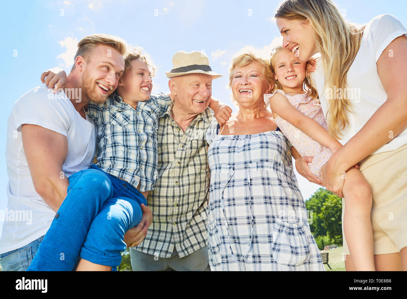 Three generations of family with grandparents and children laughs ...