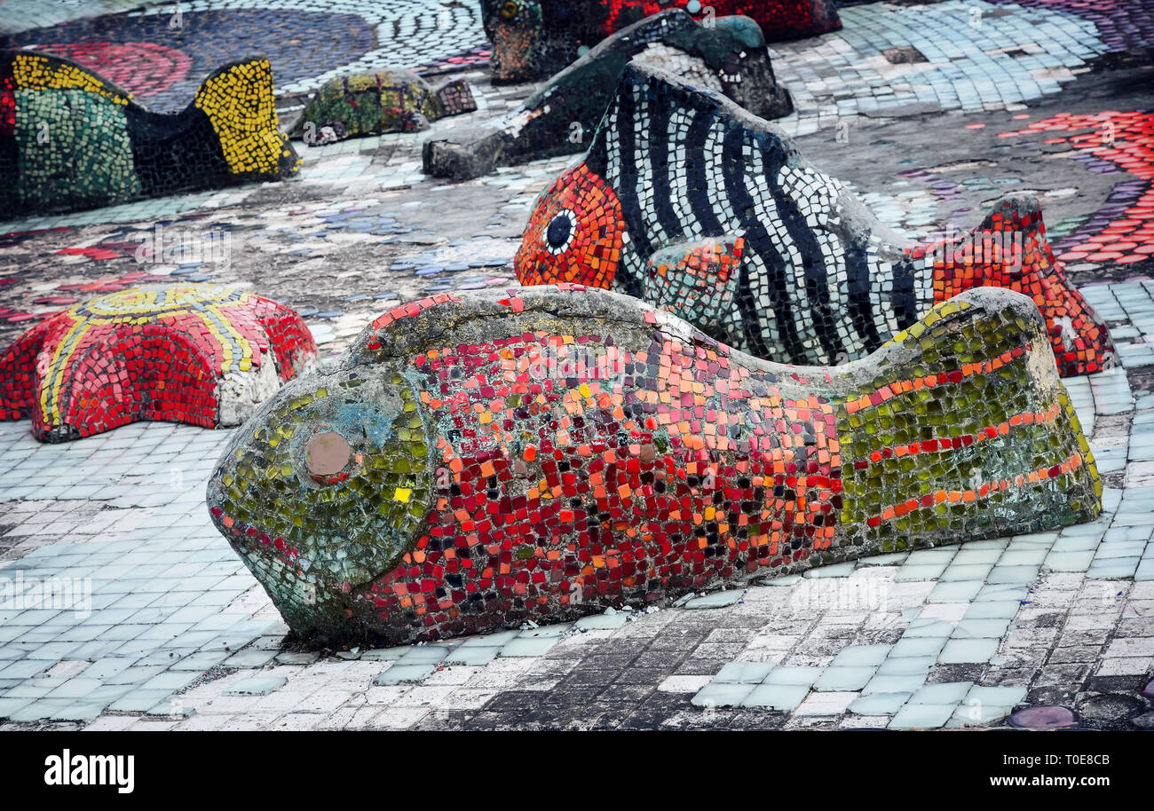 On the ceramic tiled shore of a small pond, there are sculptures of ...