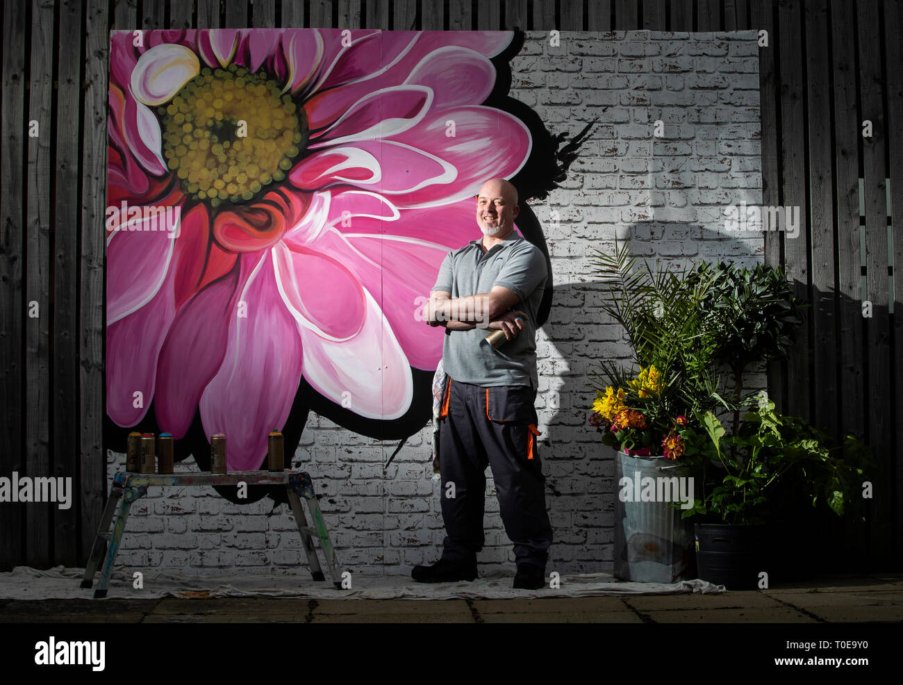 Mural artist Lee Ferry with one of his flower murals during the press ...