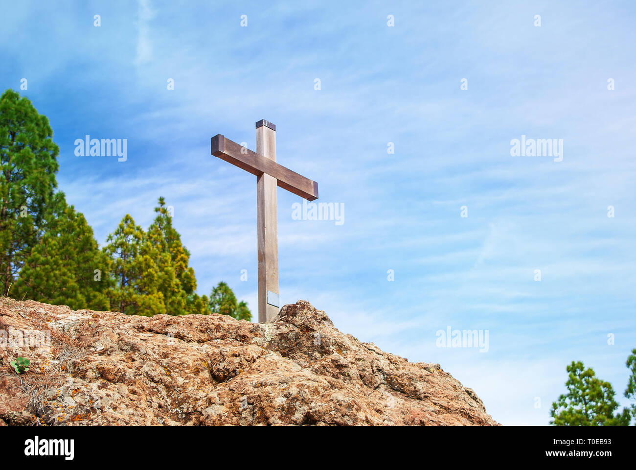 Wooden Christian cross towers on a stone rock on background of a blue ...