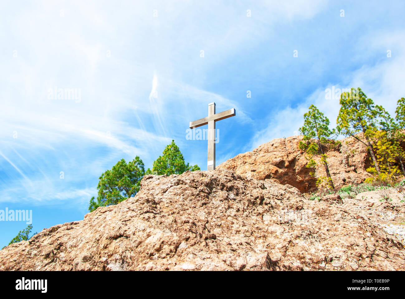 Wooden Christian cross towers on a stone rock on background of a blue ...