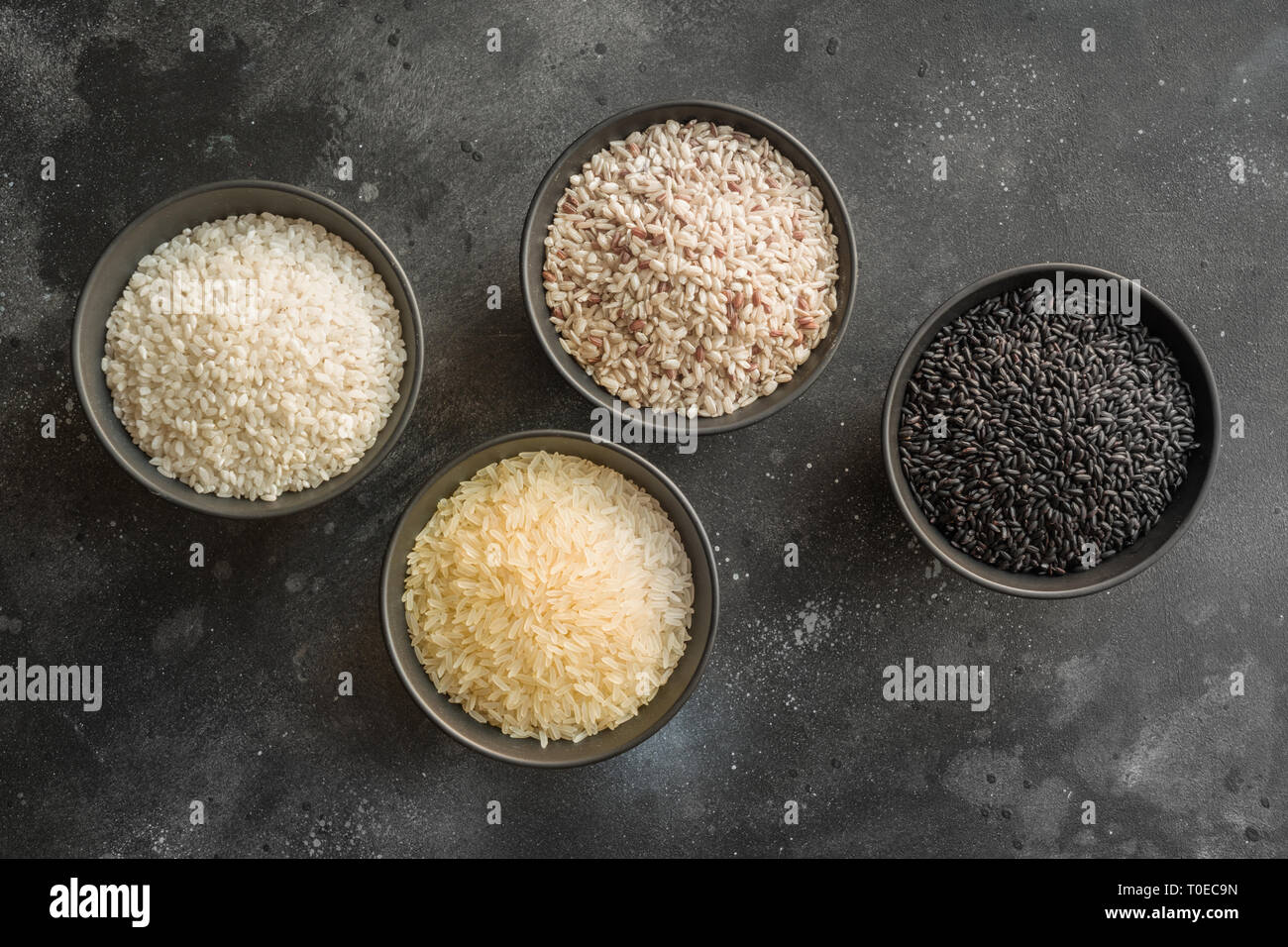 Different varieties of rice. Black rice in bowl on black background ...