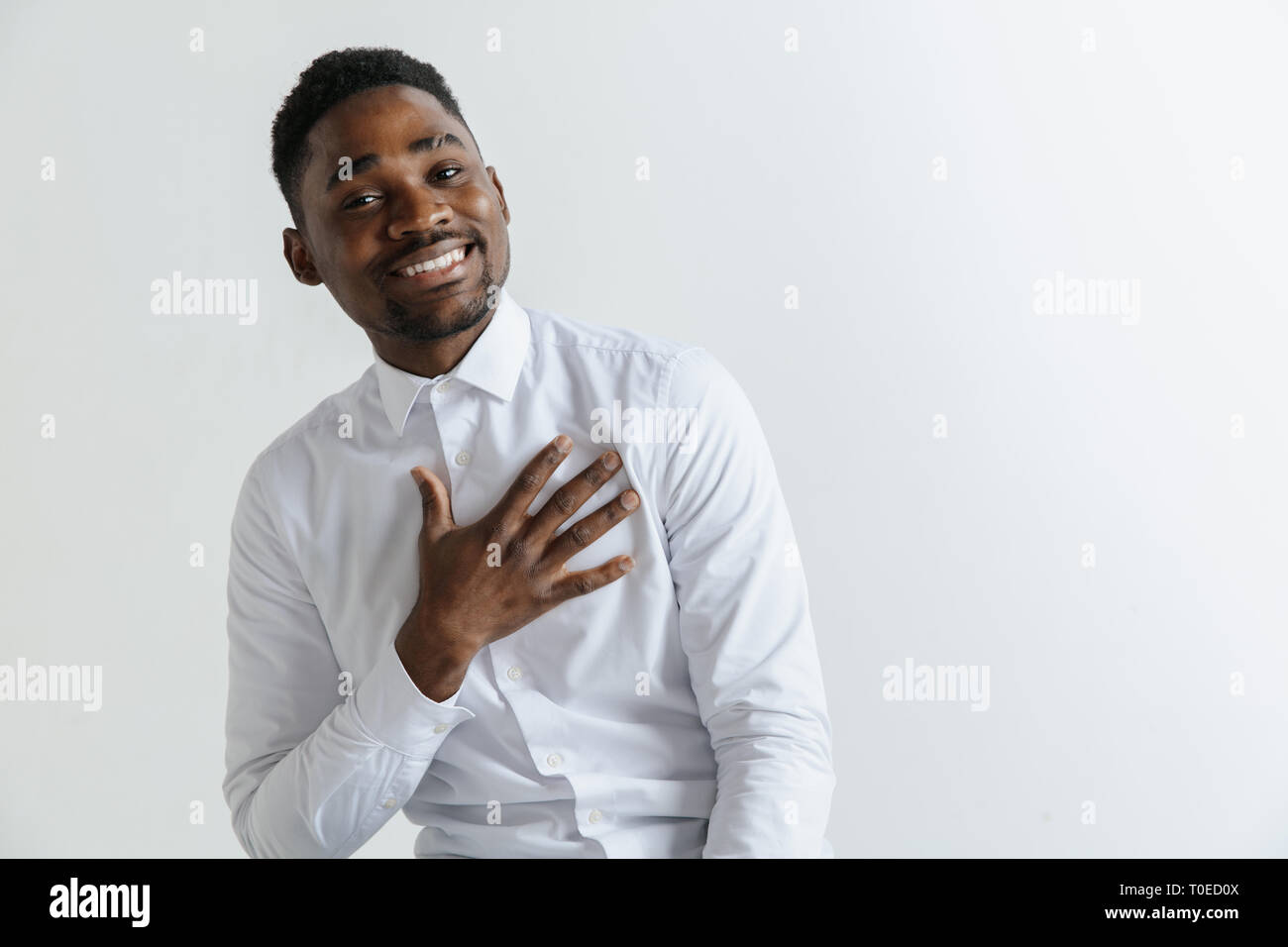 Grateful happy pleased african man holding hands on chest to heart ...