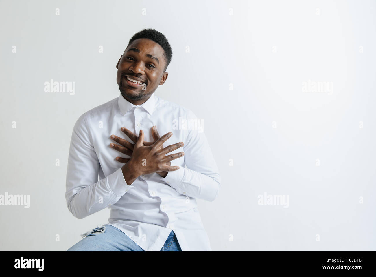 Grateful happy pleased african man holding hands on chest to heart ...