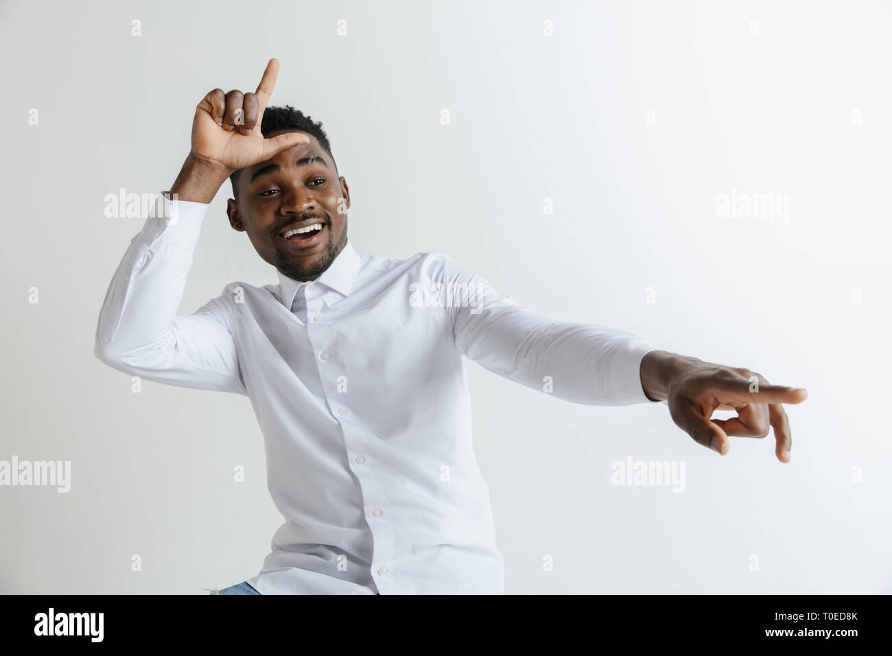 Losers go home. Portrait of happy guy showing loser sign over forehead ...