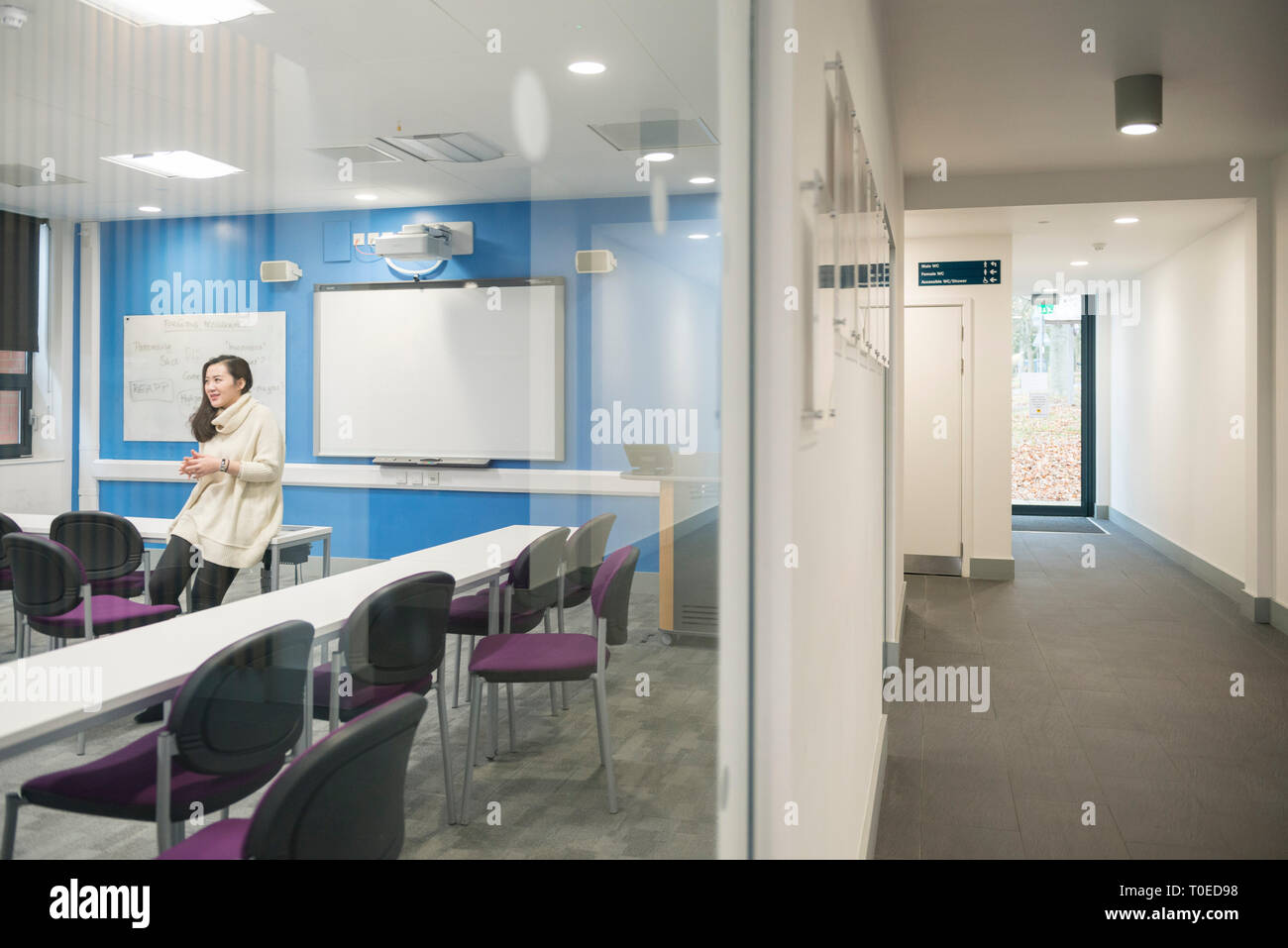 A female student sits on a desk in a classroom in sussex univeristy and ...