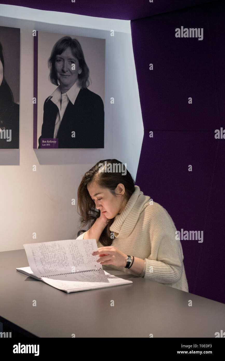 A young asian woman sits and works while reading in the modern communal ...