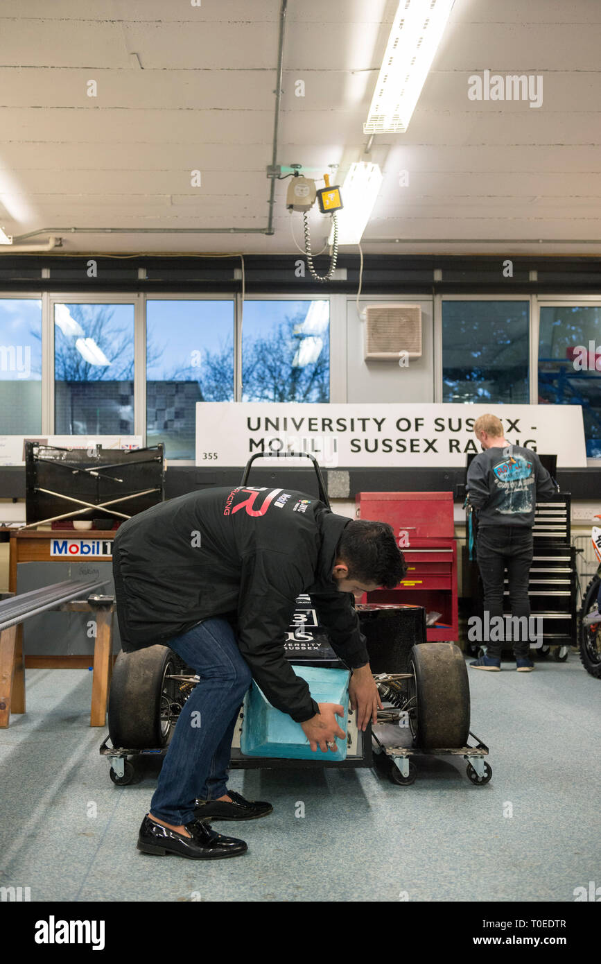A young international muslim student woking on a racing motorsport cart ...