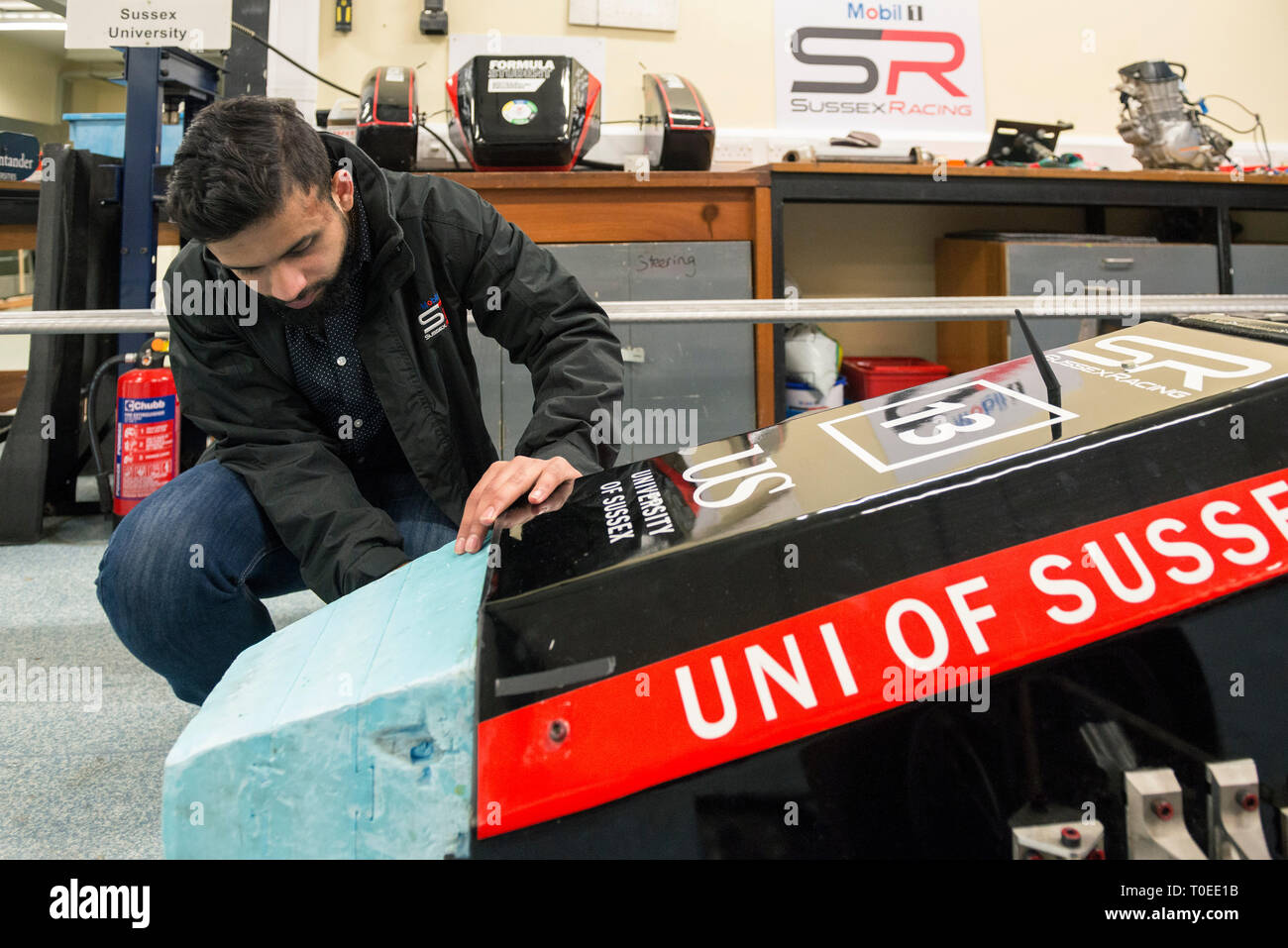 A young international muslim student woking on a racing motorsport cart ...