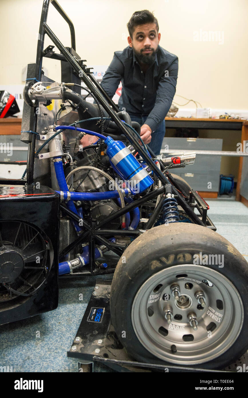 A young international muslim student woking on a racing motorsport cart ...